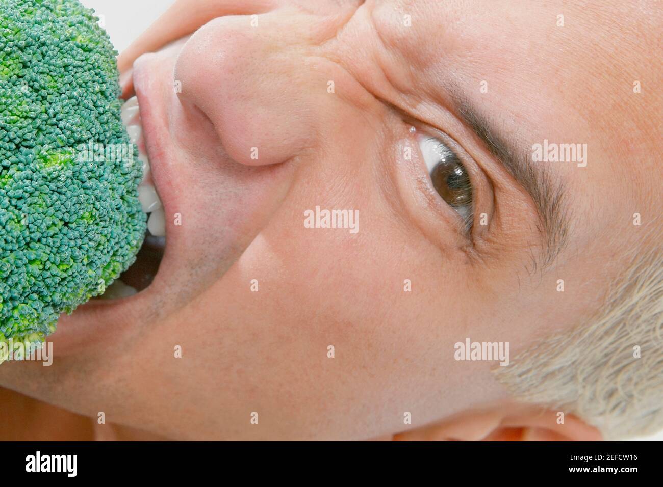 Portrait of a young man eating broccoli Stock Photo - Alamy
