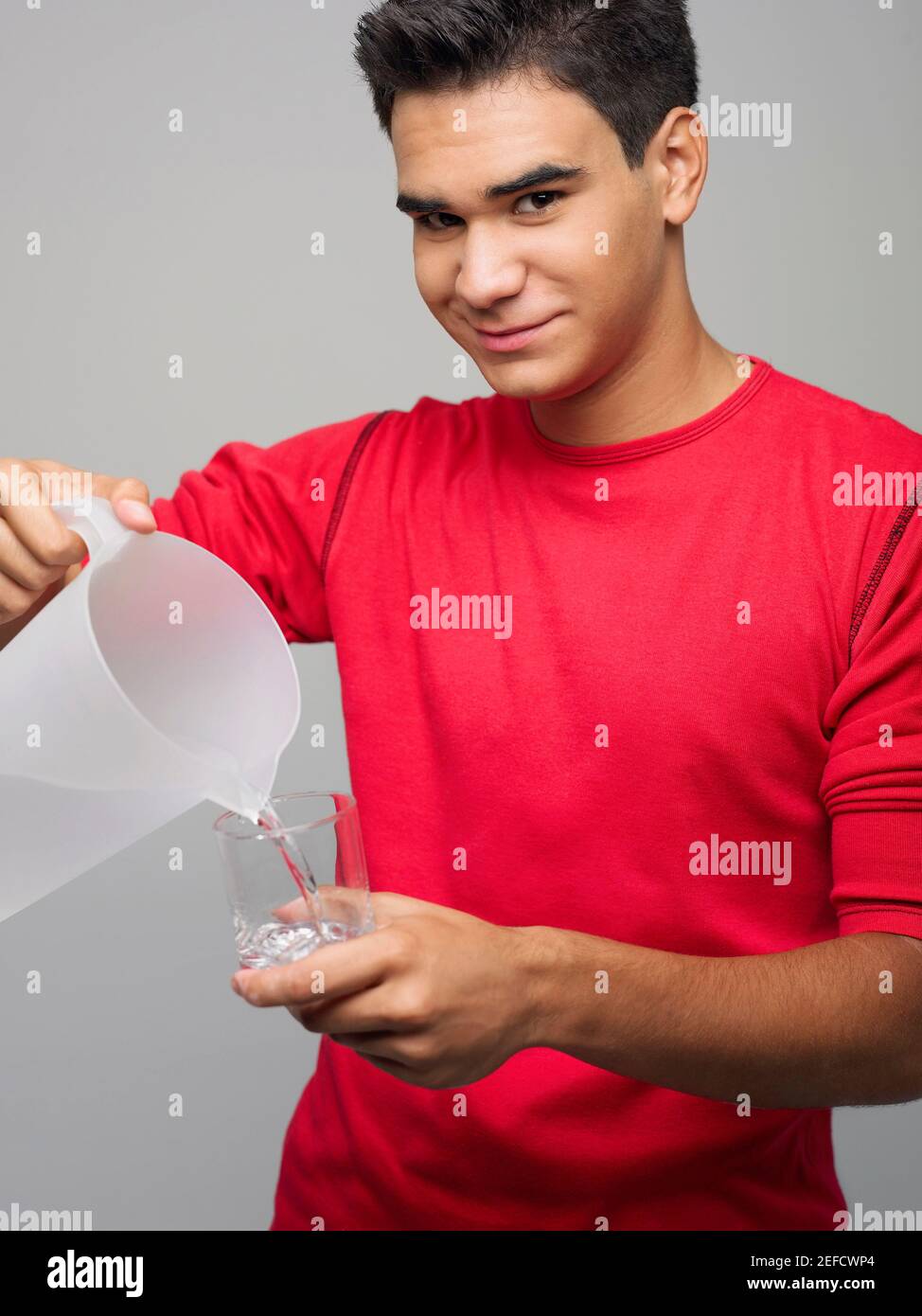 Portrait of a young man pouring water in a glass from a jug Stock Photo ...
