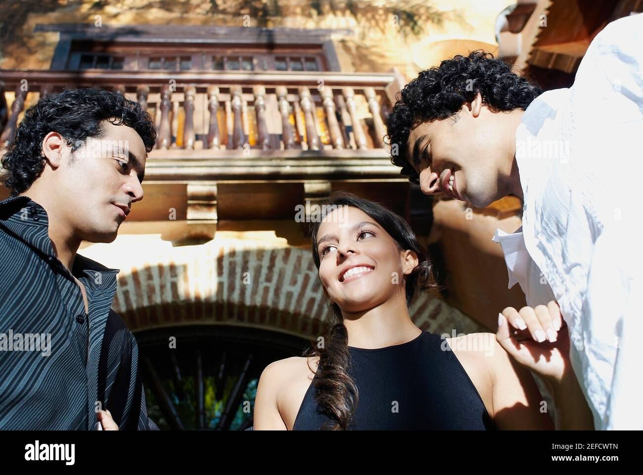 Low angle view of a teenage girl smiling with two young men Stock Photo ...