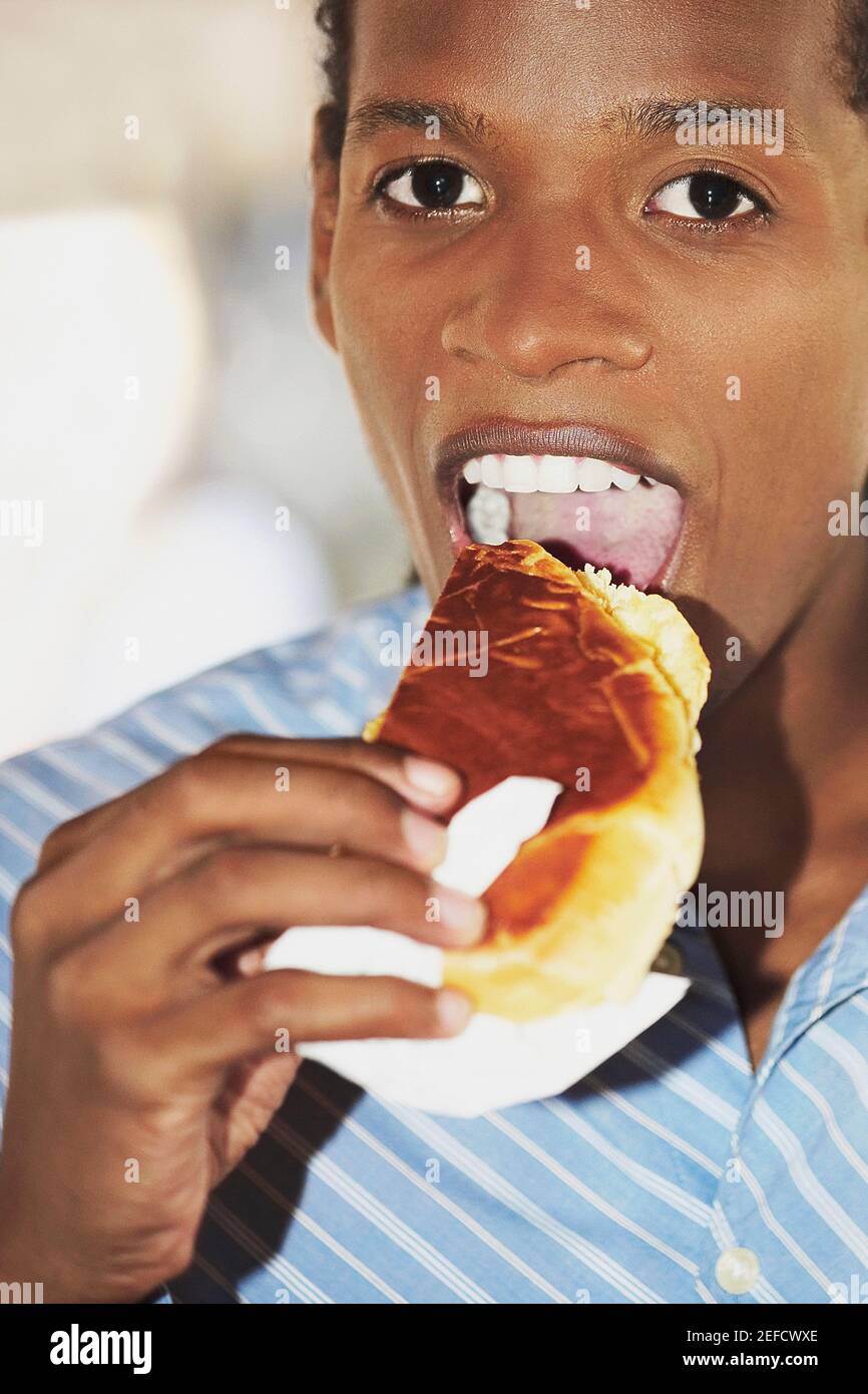 Portrait of a young man eating a pastry Stock Photo - Alamy