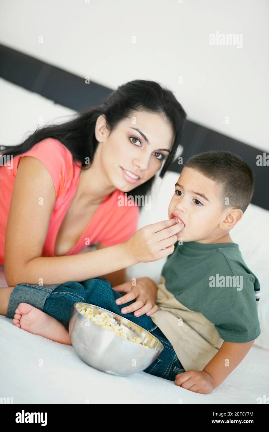 Portrait of a young woman feeding popcorn to her son Stock Photo - Alamy