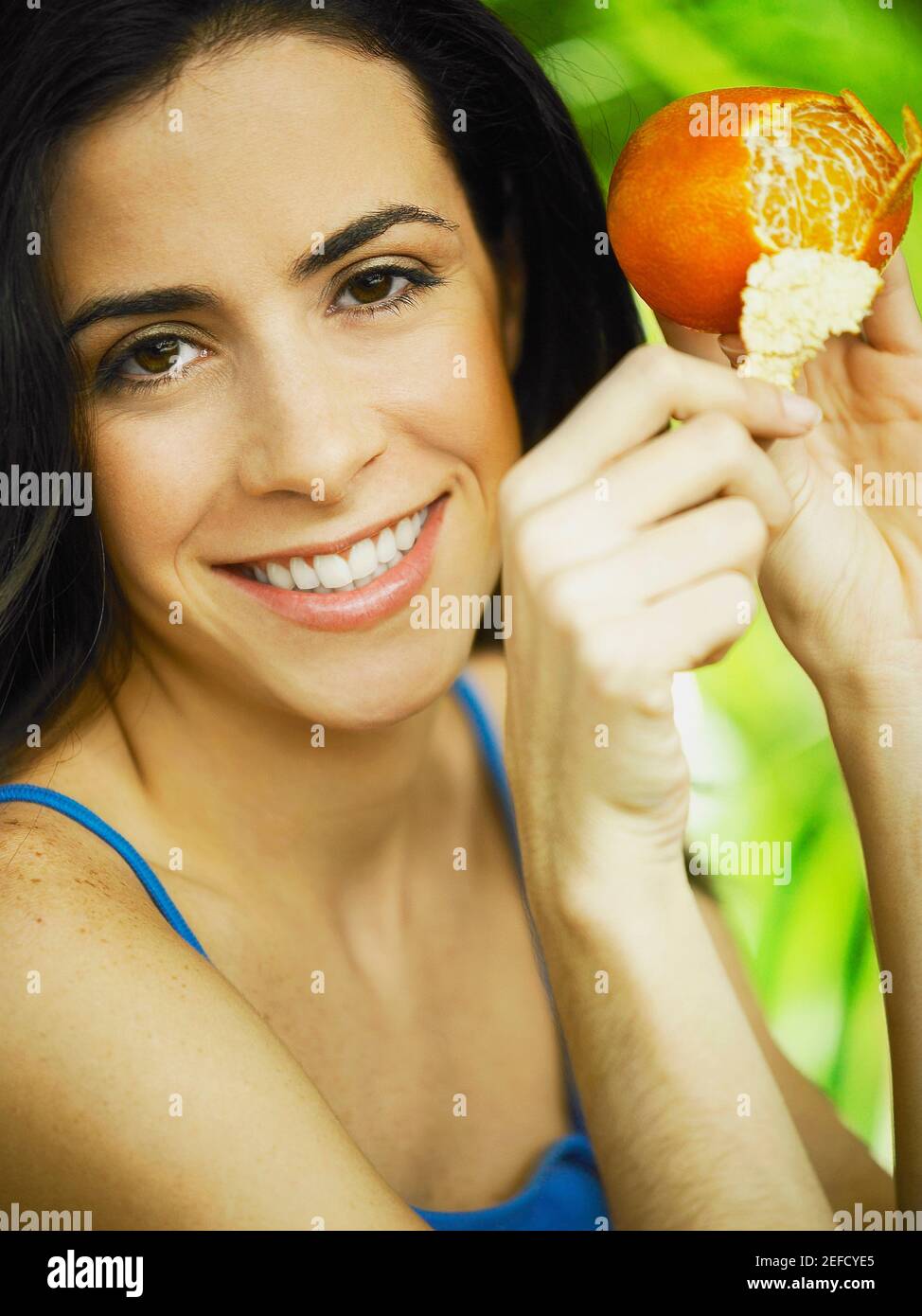 Portrait of a young woman peeling an orange Stock Photo - Alamy
