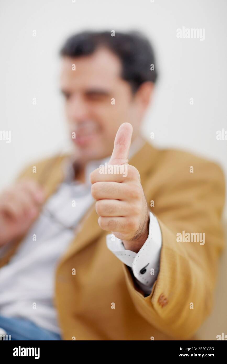 Mid adult man giving a thumbs up sign Stock Photo - Alamy
