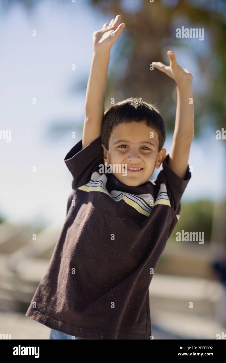 Portrait of a boy standing with his arms raised and smiling Stock Photo ...