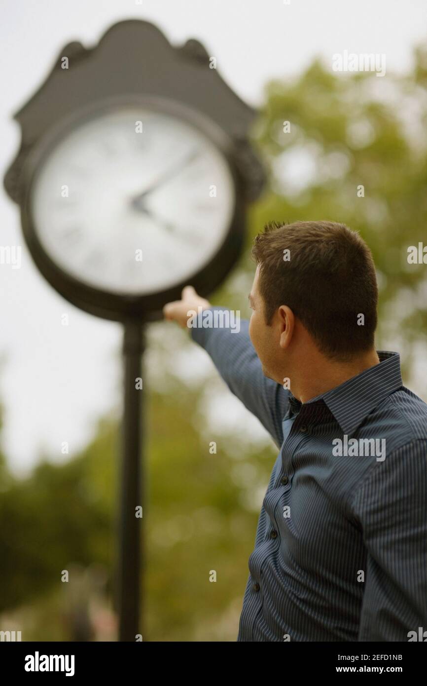 Side profile of a mid adult man pointing towards a clock Stock Photo ...