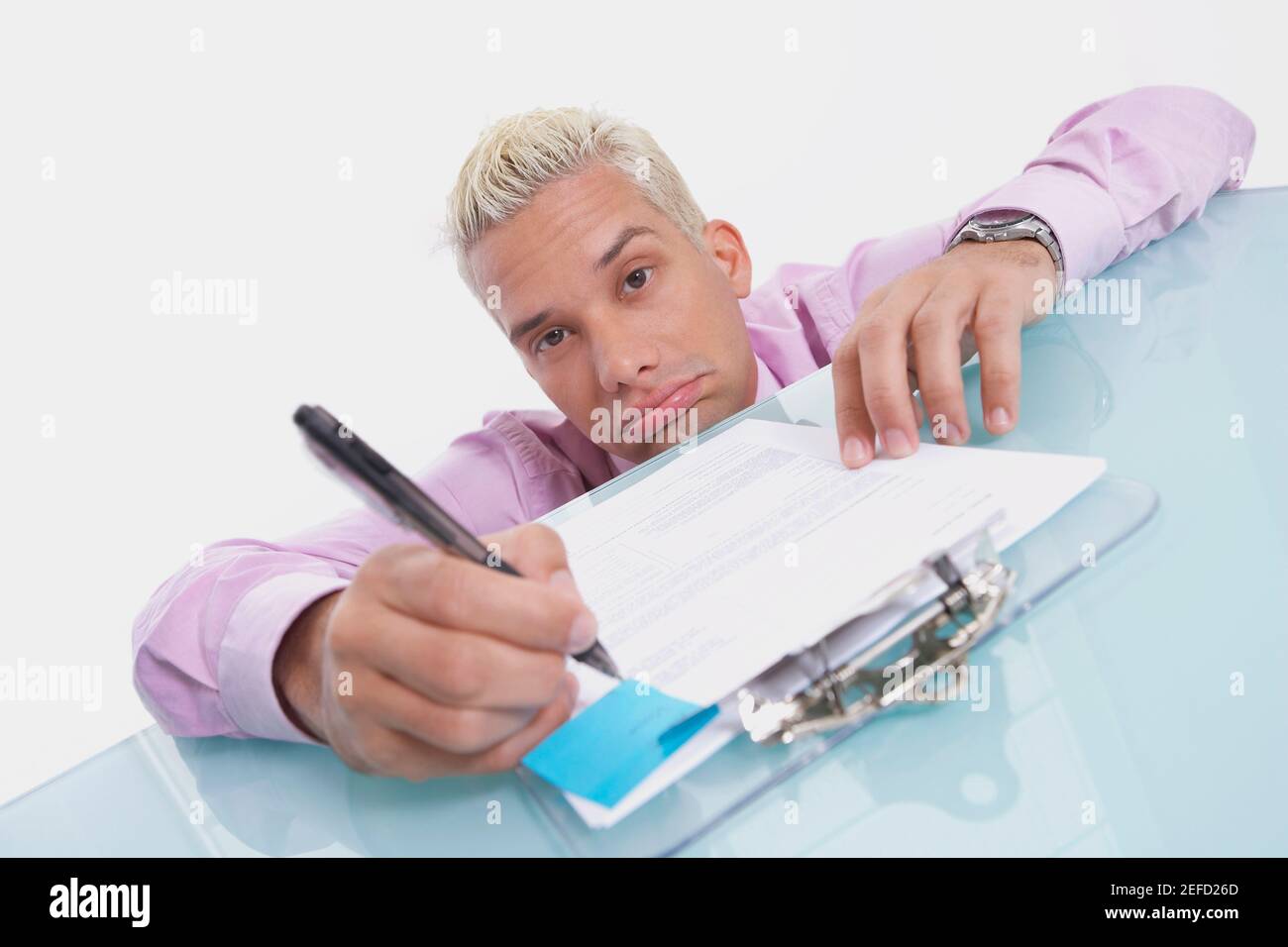 Portrait of a businessman writing on a sheet of paper and looking sad ...