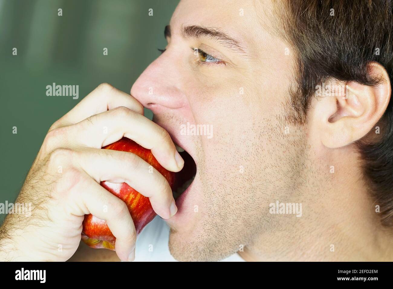 Side profile of a young man eating an apple Stock Photo - Alamy