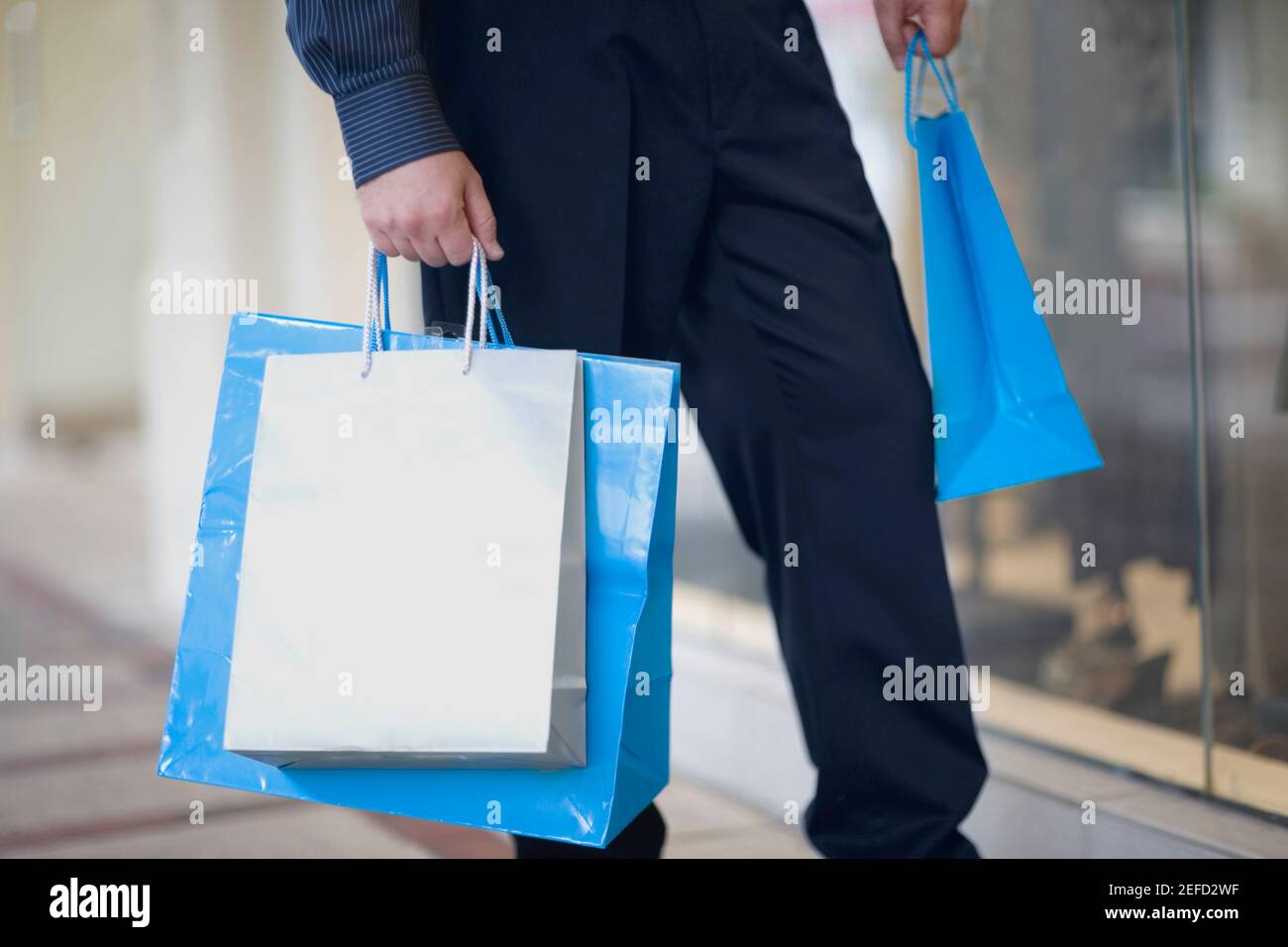 Low section view of a man carrying shopping bags Stock Photo - Alamy