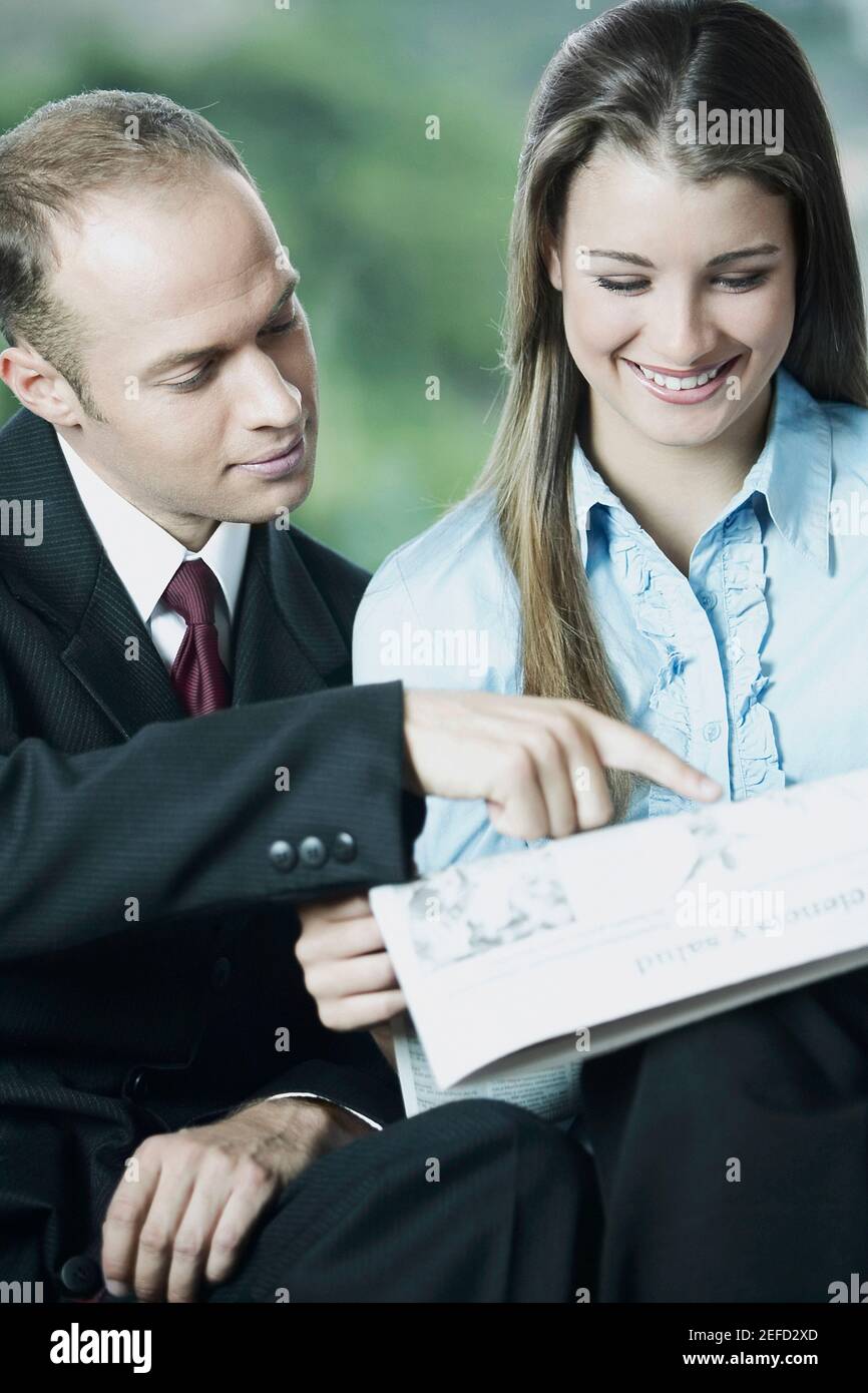 Close up of a businessman pointing at a newspaper held by a teenage ...