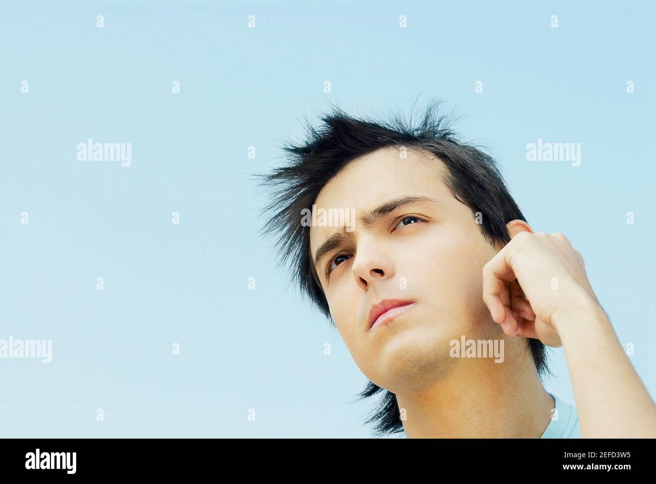 Low angle view of a young man thinking Stock Photo - Alamy