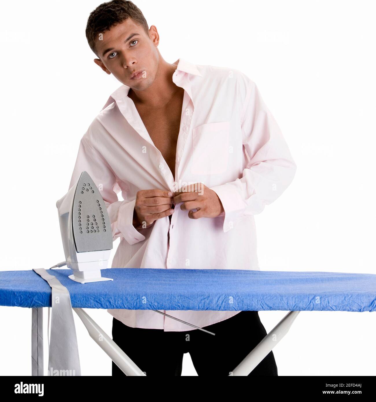 Portrait of a young man buttoning his shirt Stock Photo - Alamy