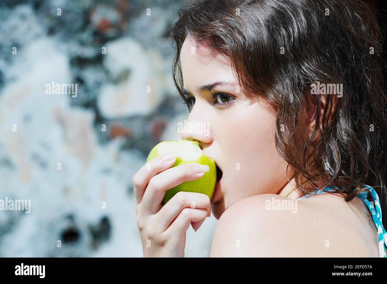 Side profile of a young woman eating a green apple Stock Photo - Alamy