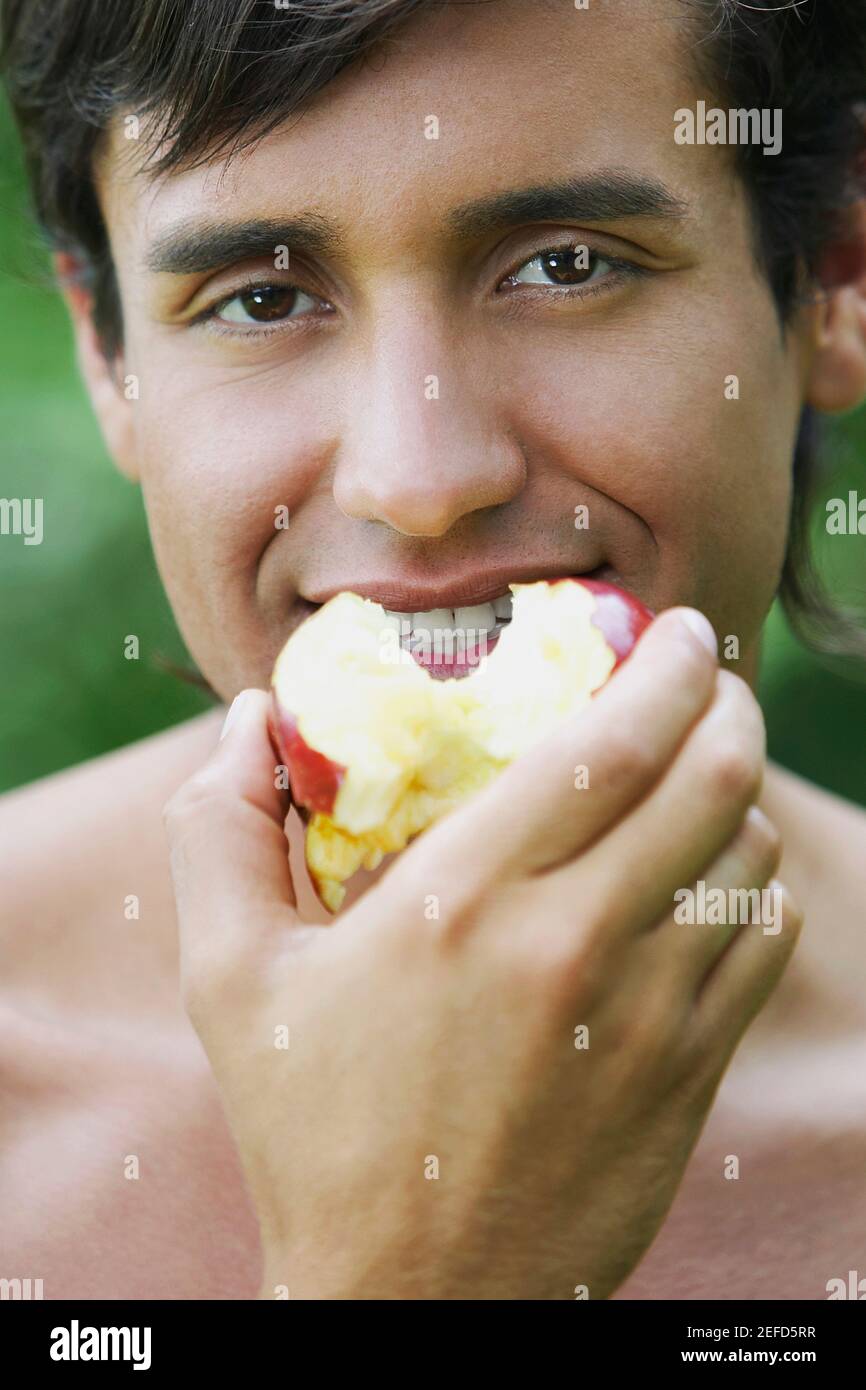 Portrait of a young man eating an apple Stock Photo - Alamy