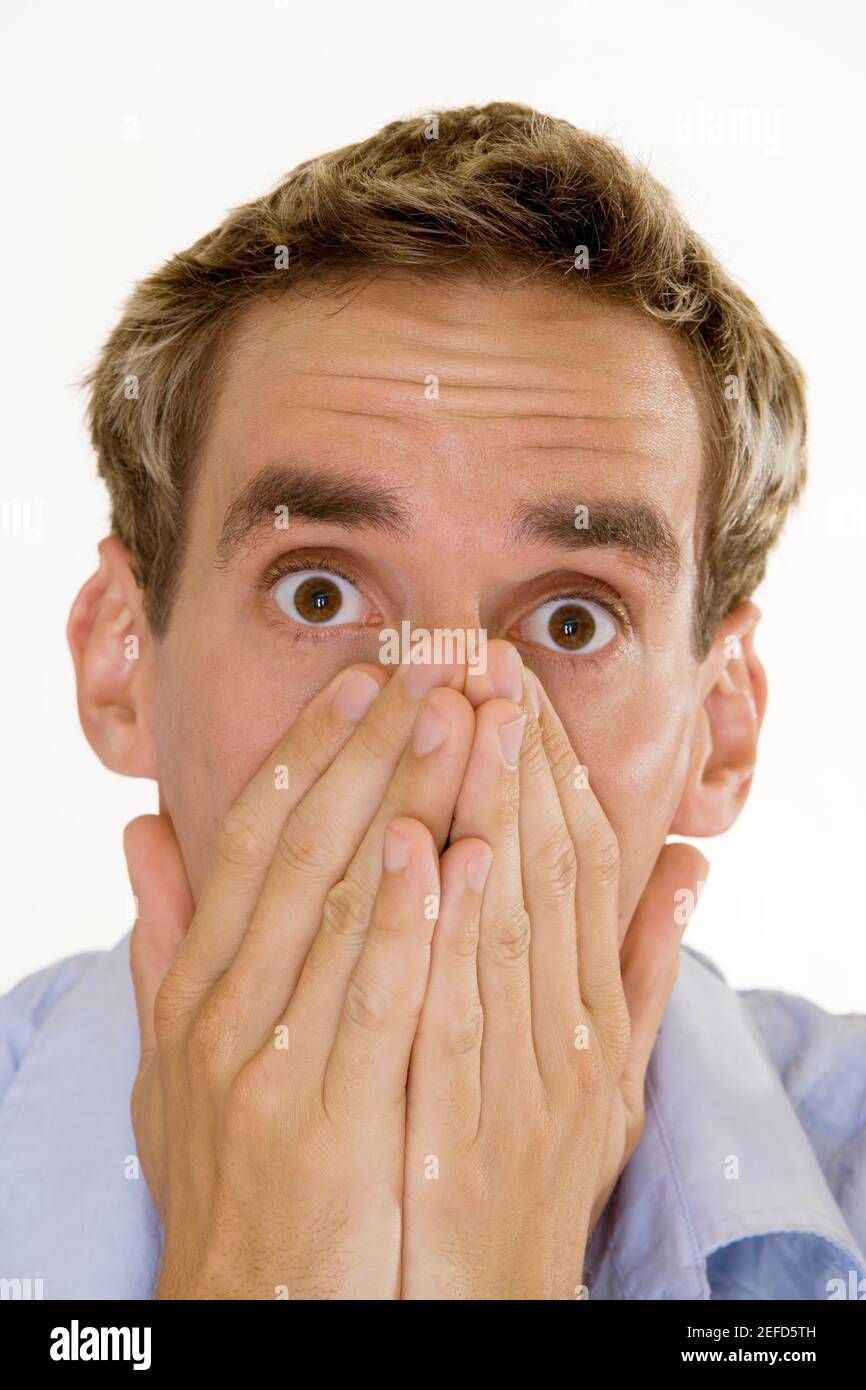 Portrait of a young man covering his mouth with his hands Stock Photo ...