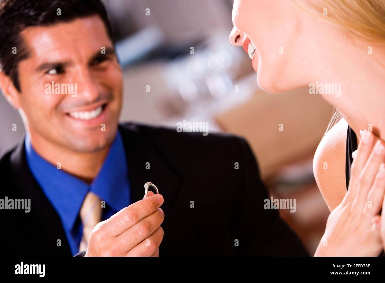 Mid adult man giving an engagement ring to a young woman Stock Photo ...