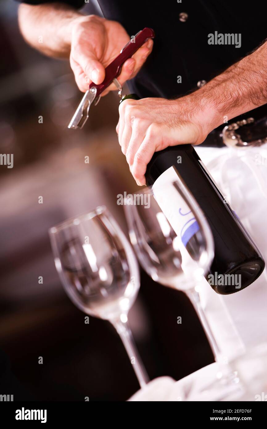 Mid section view of a man opening the cork of a wine bottle Stock Photo ...