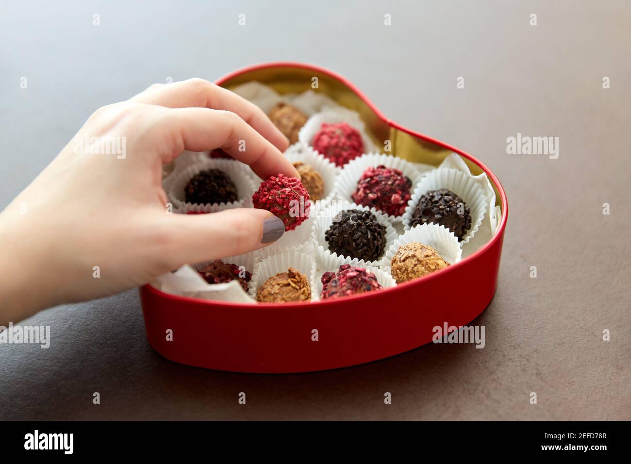 hand with candies in heart shaped chocolate box Stock Photo - Alamy