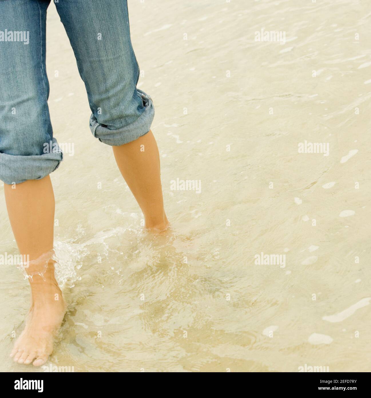 Low section view of a young woman wading in water on the beach Stock ...