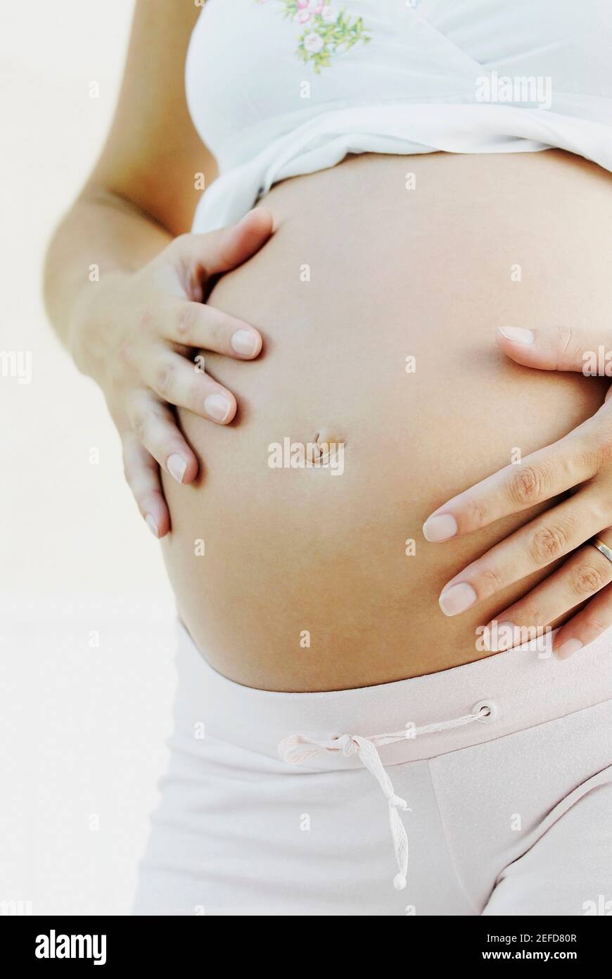 Mid section view of a pregnant woman touching her abdomen Stock Photo ...
