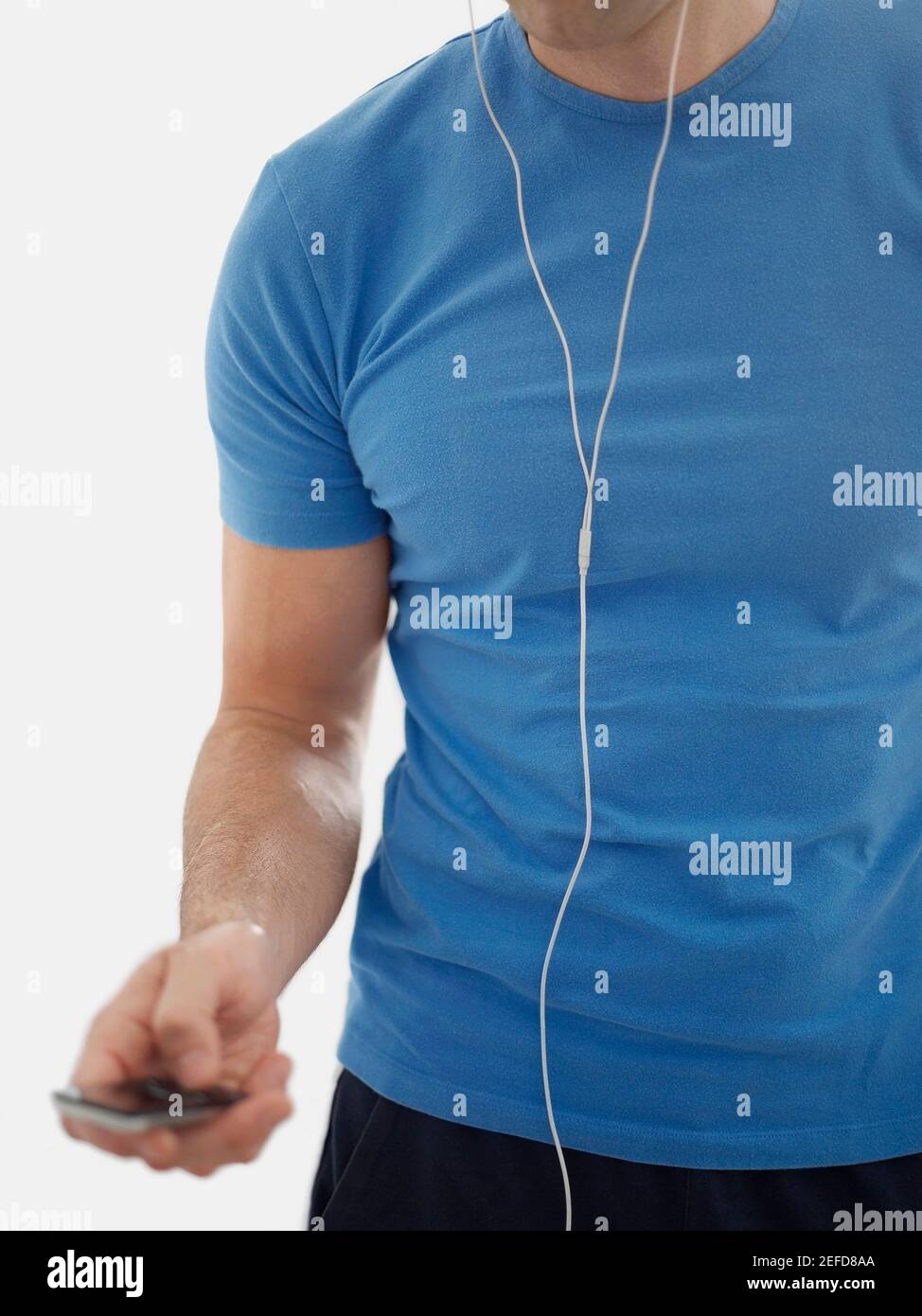 Mid section view of an unrecognizable person listening to an MP3 player ...