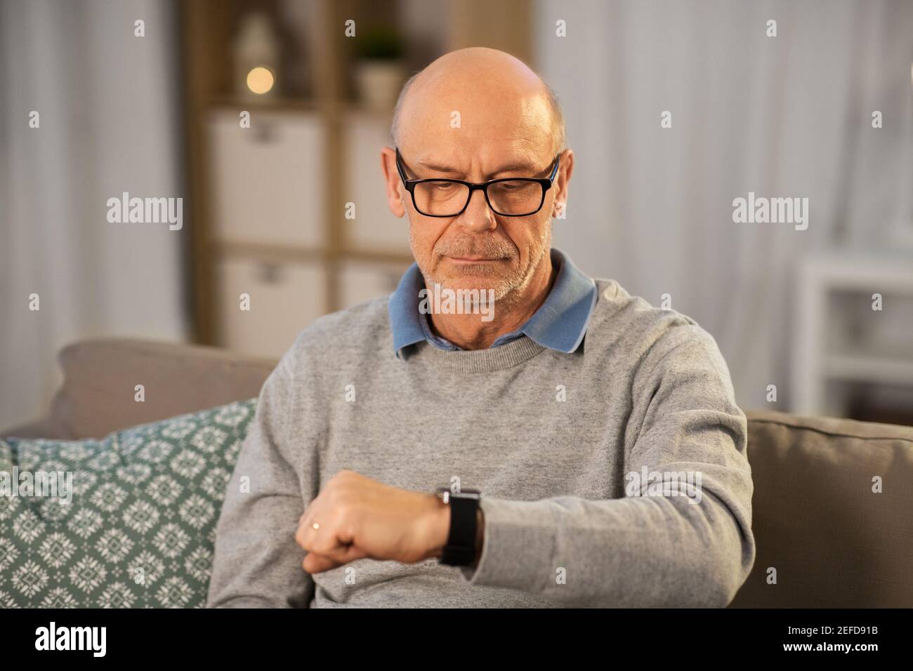 senior man looking at wristwatch at home Stock Photo - Alamy
