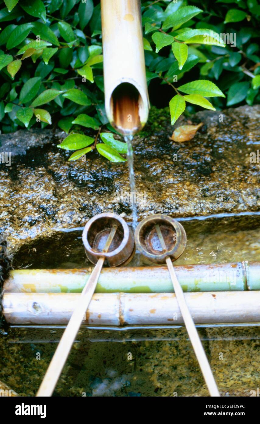 High angle view of water flowing from a bamboo pipe into a rock garden ...