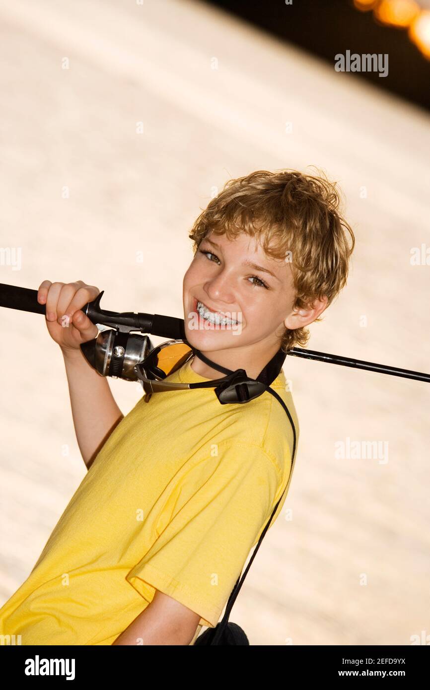 Portrait of a boy smiling carrying a fishing rod Stock Photo - Alamy