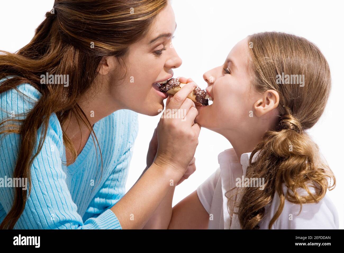 Side profile of a mother and her daughter eating a pastry Stock Photo ...