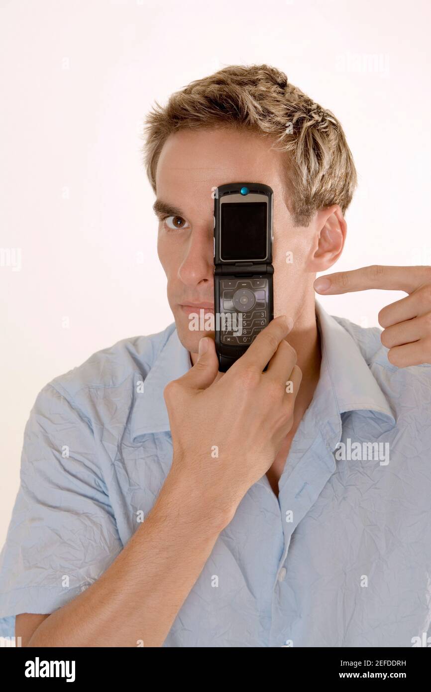 Portrait of a young man pointing to a mobile phone in his hand Stock ...