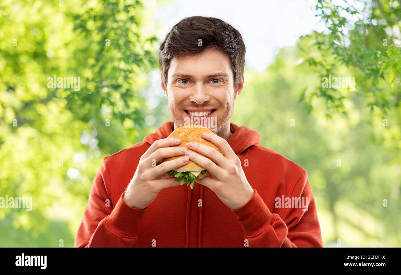 happy young man eating hamburger Stock Photo - Alamy