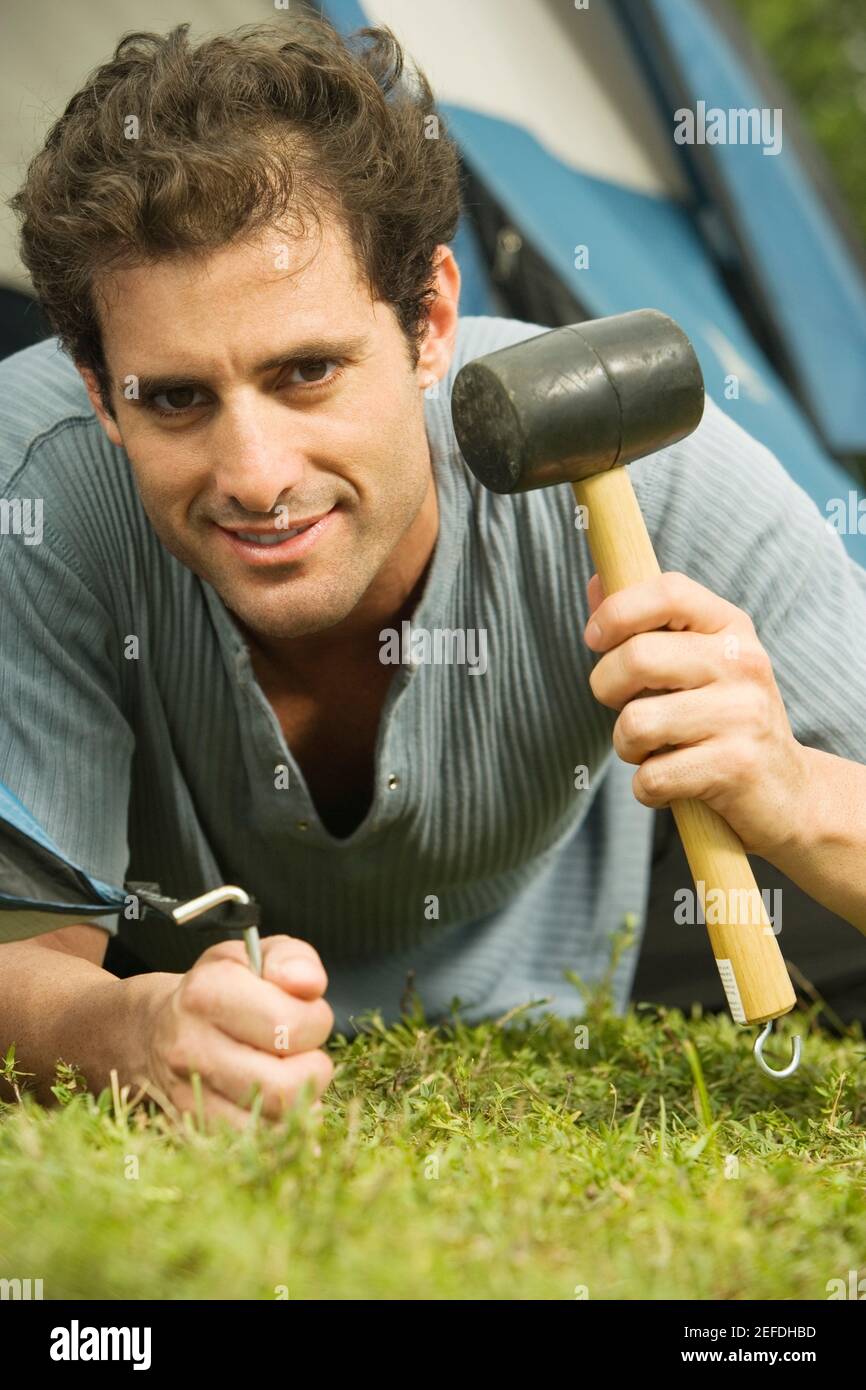 Portrait of a young man putting up a tent Stock Photo - Alamy