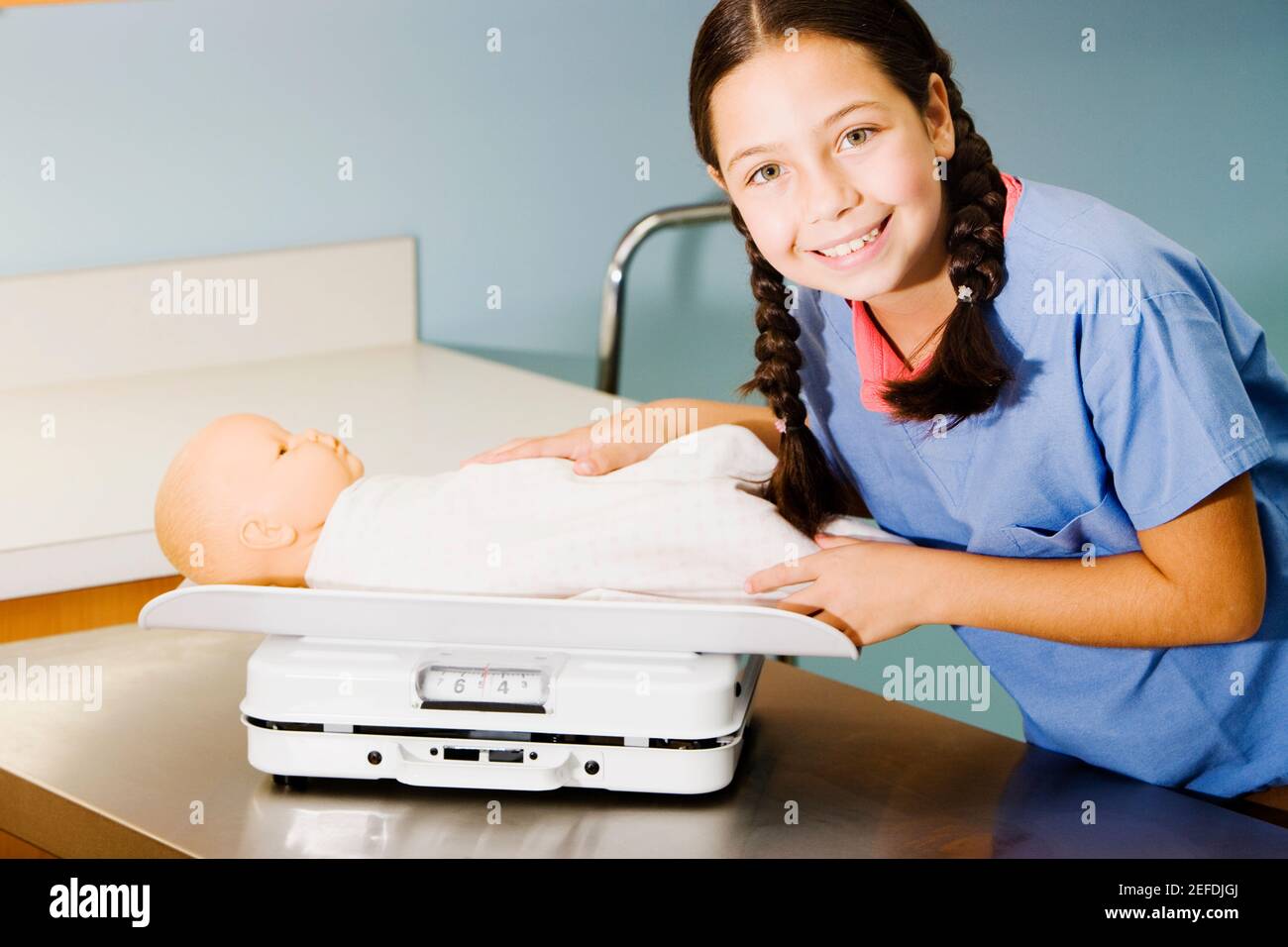 Portrait of a girl weighing a doll on a weighing scale Stock Photo - Alamy