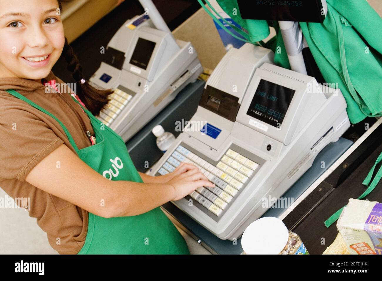 Portrait of a girl using a cash register at the checkout counter and ...