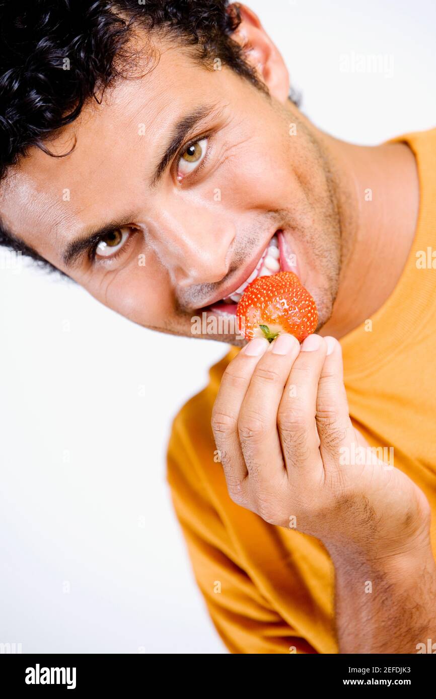 Portrait of a young man eating a strawberry Stock Photo - Alamy