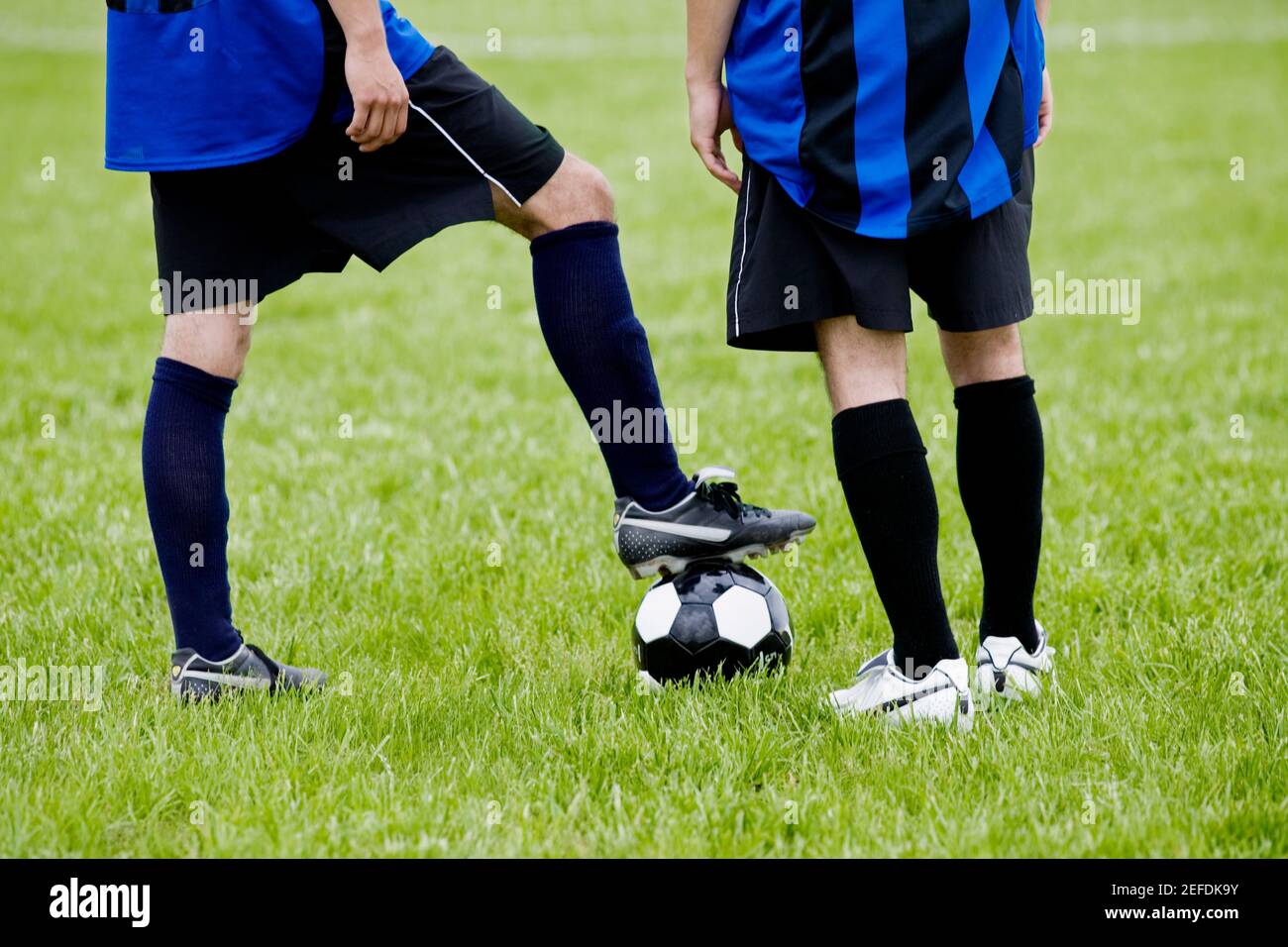 Low section view of a soccer player resting his foot on a soccer ball ...