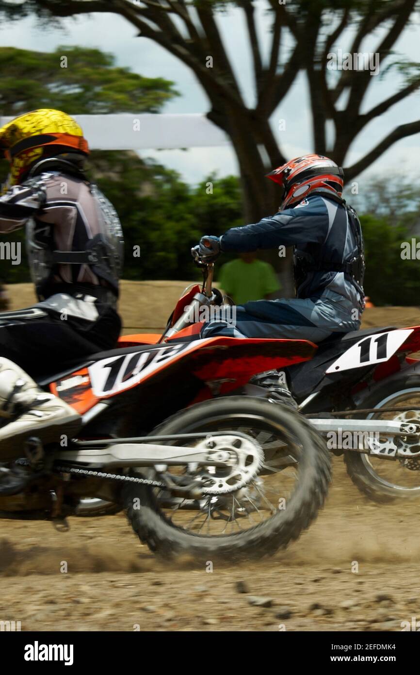 Side profile of two motocross riders riding motorcycles Stock Photo - Alamy
