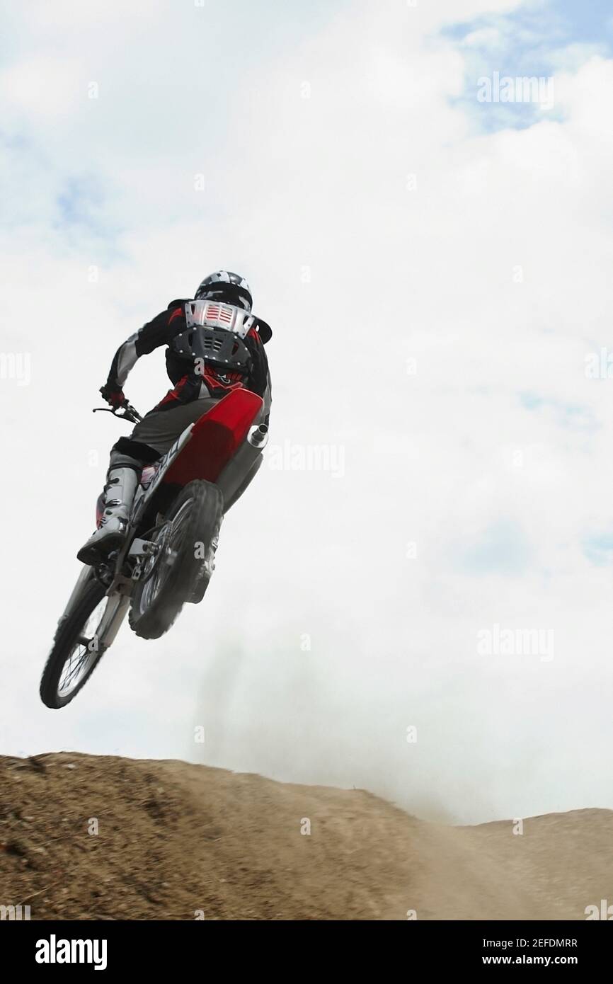 Low angle view of a motocross rider performing a jump on a motorcycle ...