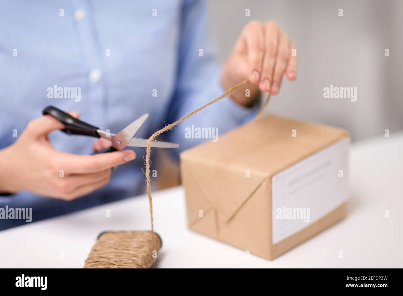 woman with parcel cutting rope at post office Stock Photo - Alamy