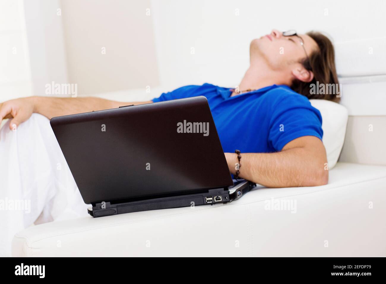 Side profile of a young man reclining on a couch Stock Photo - Alamy