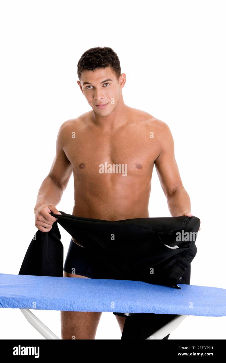 Portrait of a young man standing and holding his pants in front of an ...