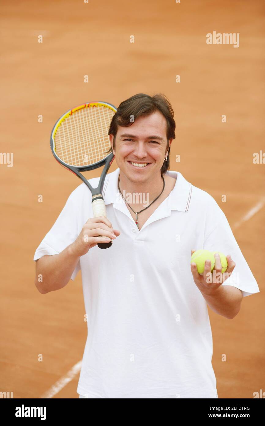 Portrait of a mid adult man holding tennis balls and a tennis racket ...