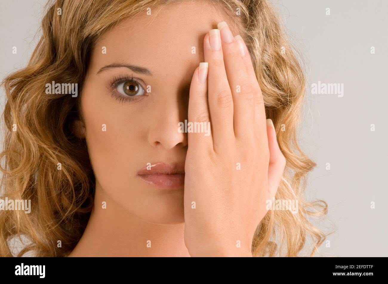 Portrait of a young woman covering her one eye Stock Photo - Alamy