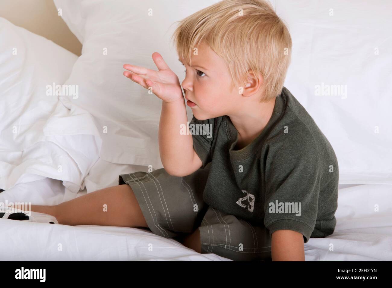 Side profile of a boy sitting on a bed Stock Photo - Alamy