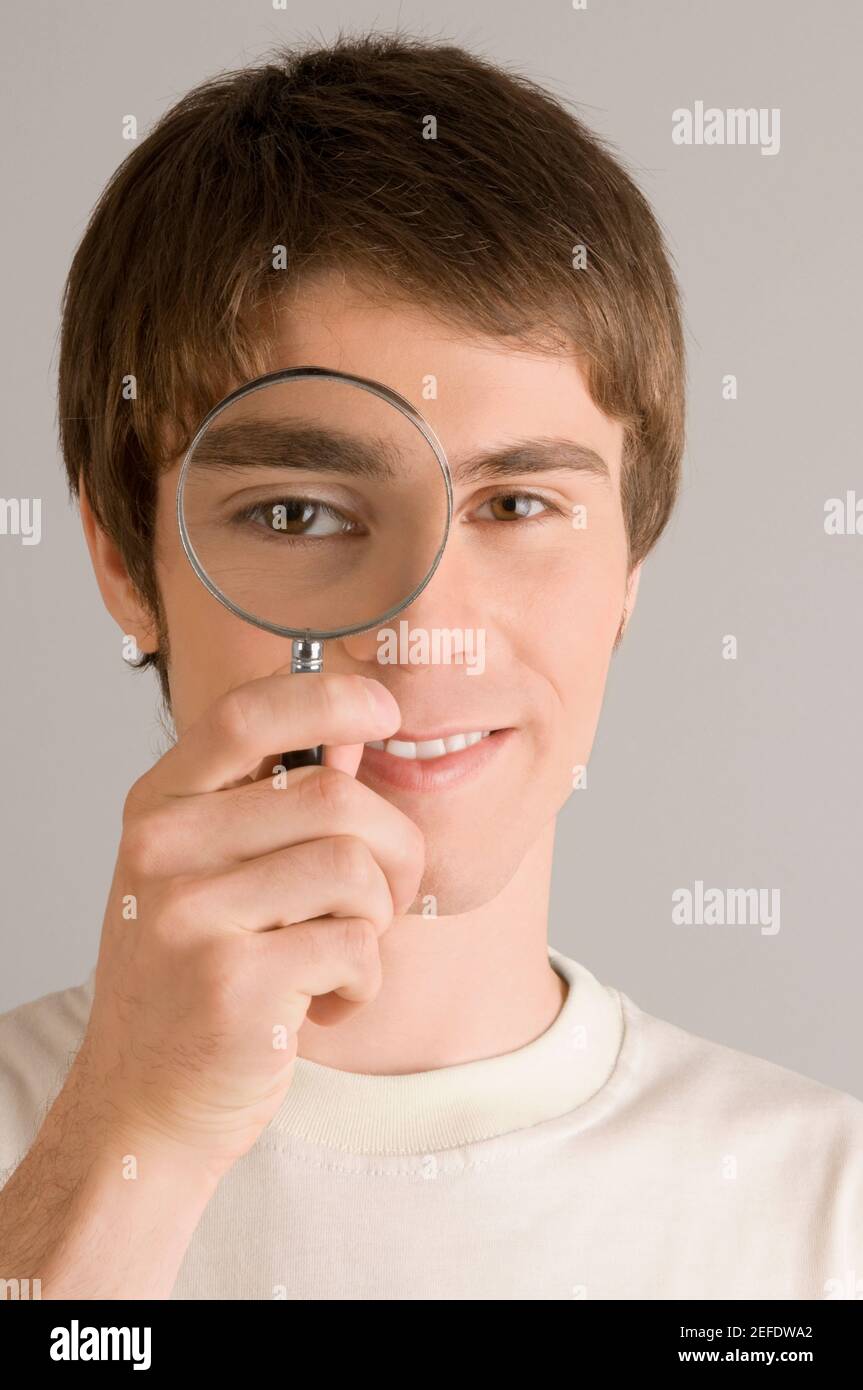 Portrait of a young man looking through a magnifying glass Stock Photo ...