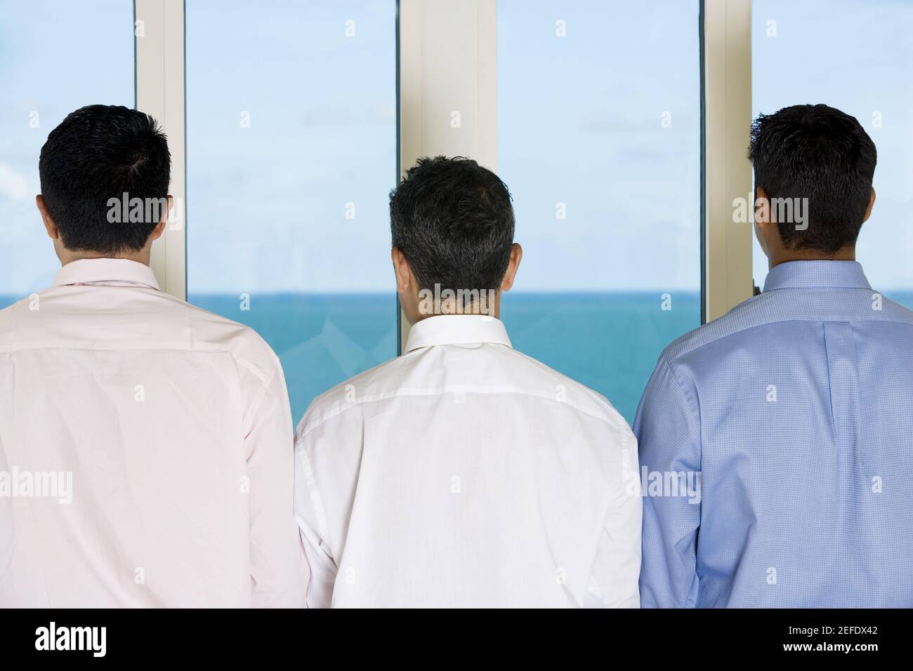 Rear view of three men standing side by side Stock Photo - Alamy