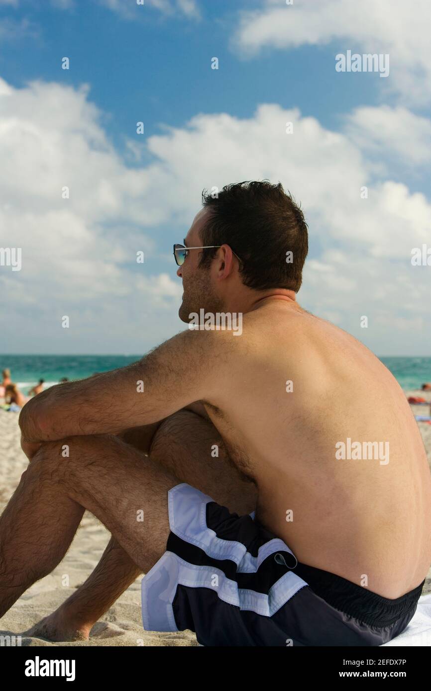 Side profile of a mid adult man sitting on the beach Stock Photo - Alamy