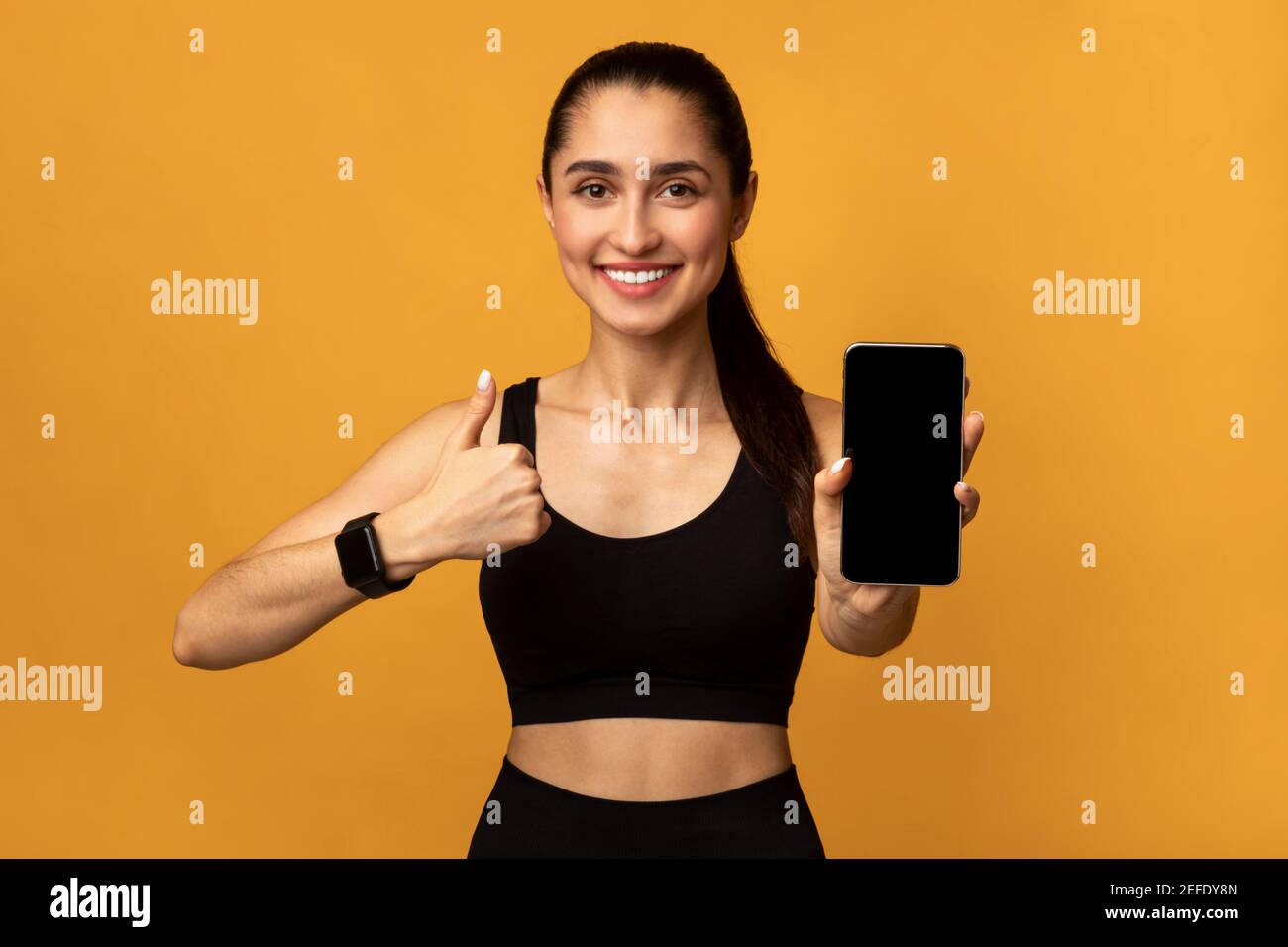 App For Healthy Lifestyle. Portrait of smiling sportswoman holding ...