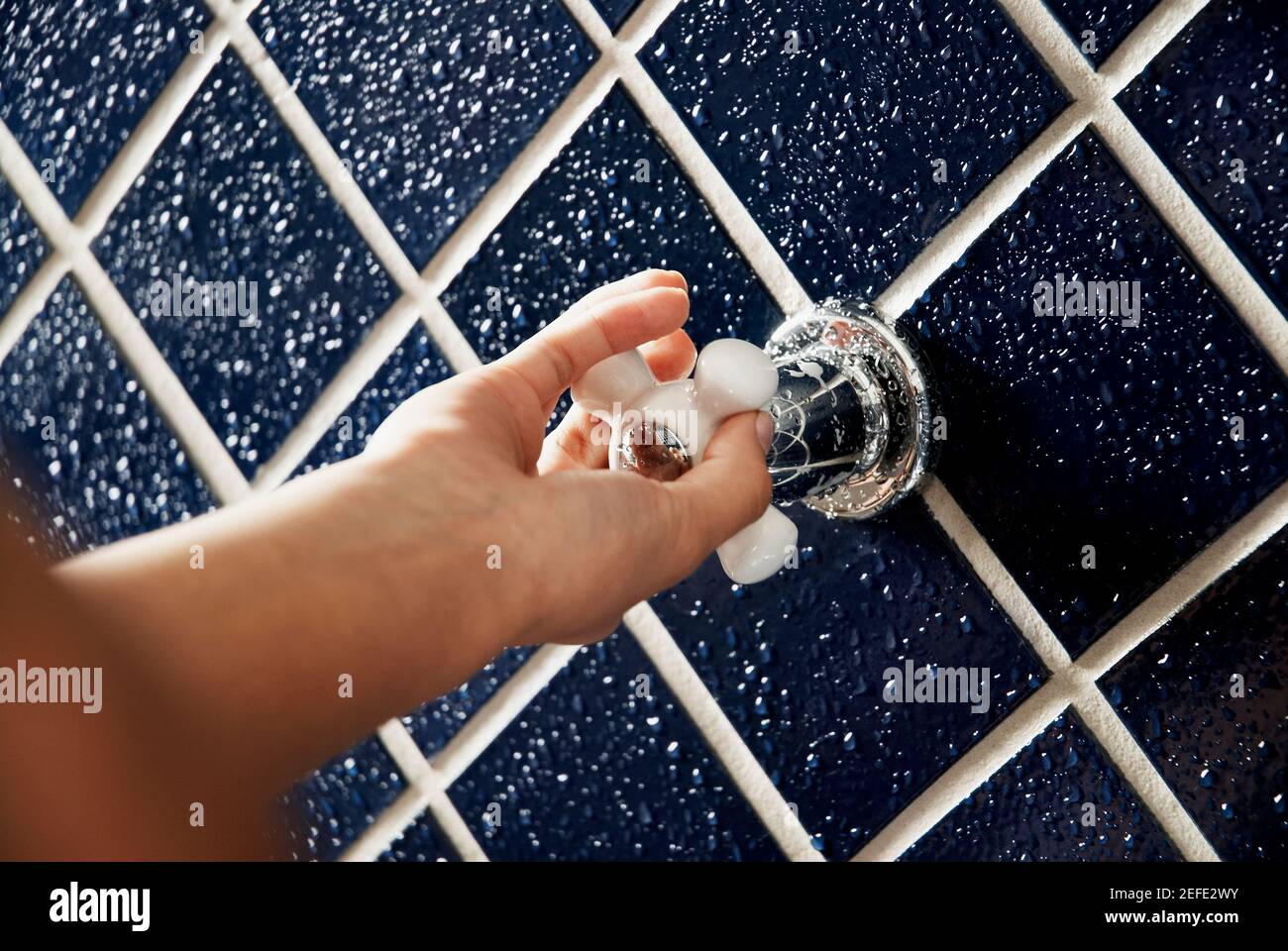 Close-up of a human hand turning a shower knob Stock Photo - Alamy
