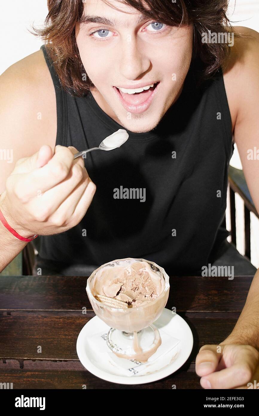 Portrait of a young man eating an ice cream sundae Stock Photo - Alamy