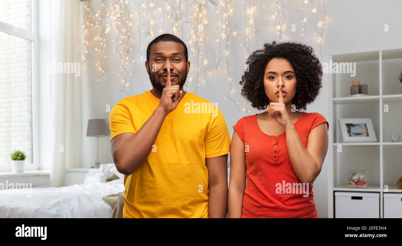 happy african american couple making hush gesture Stock Photo - Alamy